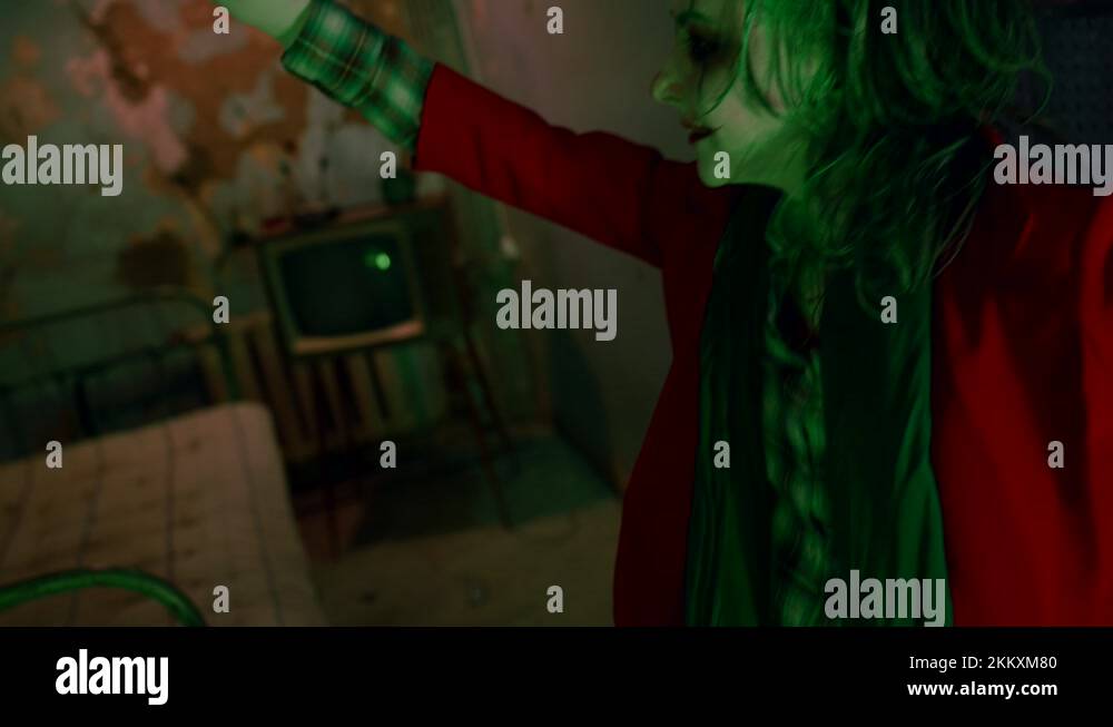 Creepy clown woman dancing in a nightmarish room. Scary clown grimaces ...