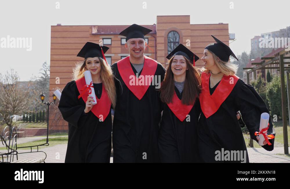 Academy graduates in gowns and certificates go to celebrate graduation ...