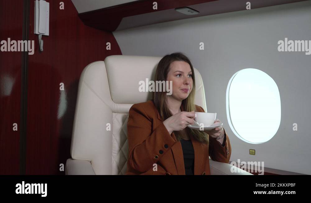 Woman in airplane cabin first business class drinking coffee. Passenger ...