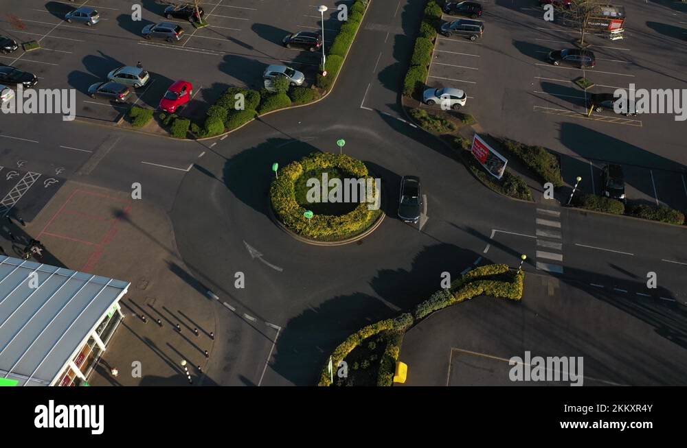 crane shot of vehicles in a roundabout infron of shopping mall parking ...