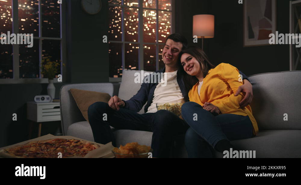 Happy married couple resting on couch together, watching funny tv ...