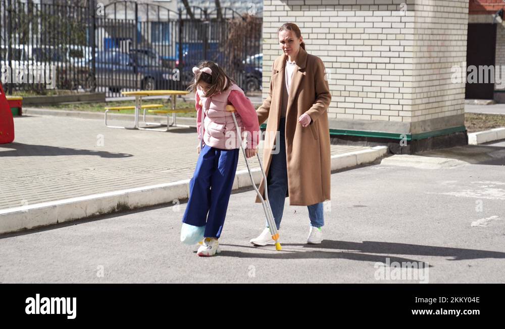 Mom Helps Daughter Learn To Walk On Crutches Plaster On Your Feet