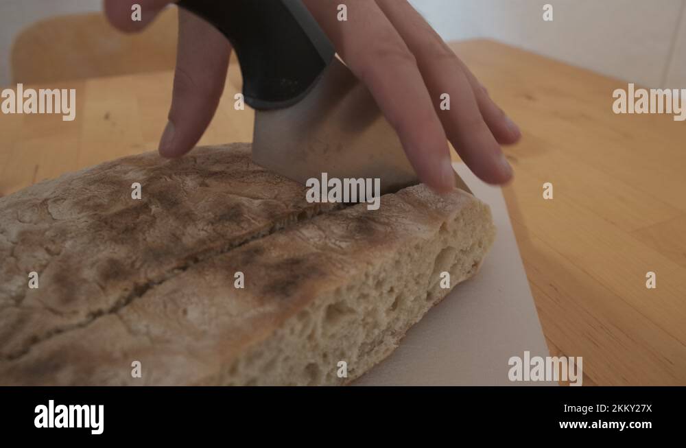 Hands cut traditional bread from Madeira called bolo do caco on wooden ...
