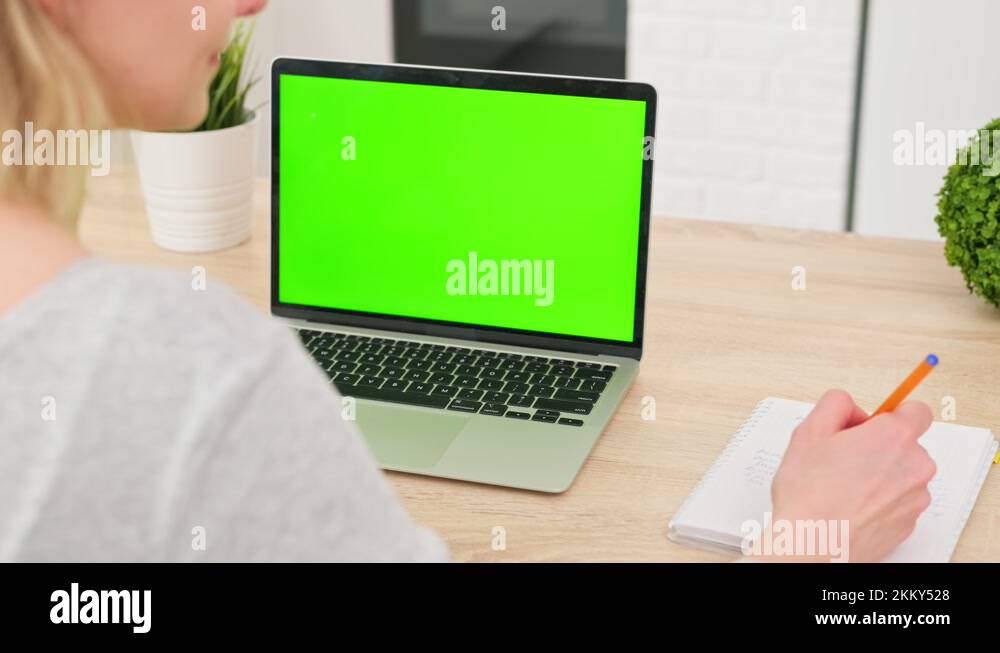 Female is listening online lecture in video conference at laptop, green ...