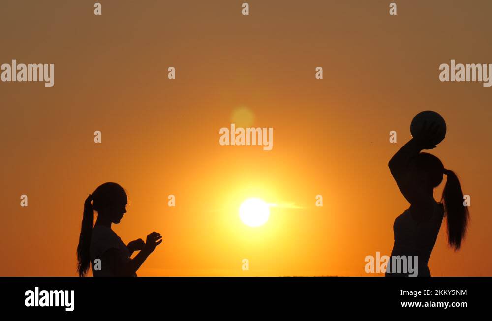 Mom and daughter are playing and throwing ball to each other under the ...