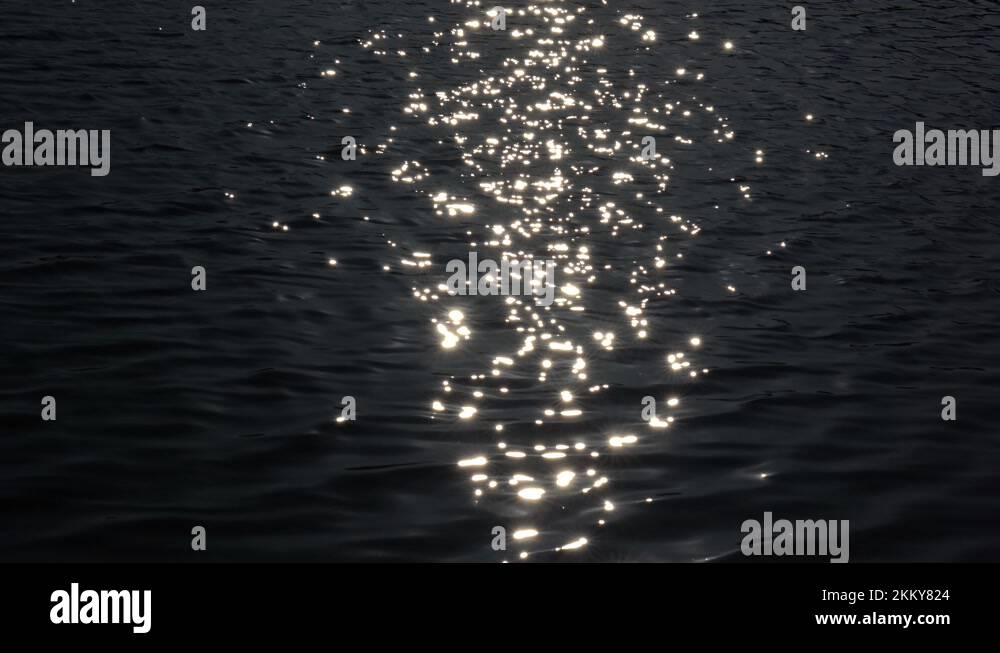 Dark texture of river rippling. Sparkling shiny sun light reflections ...