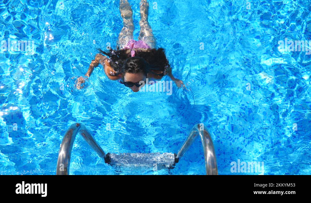 Sexy woman swimming and getting out of pool. Attractive girl in pink ...