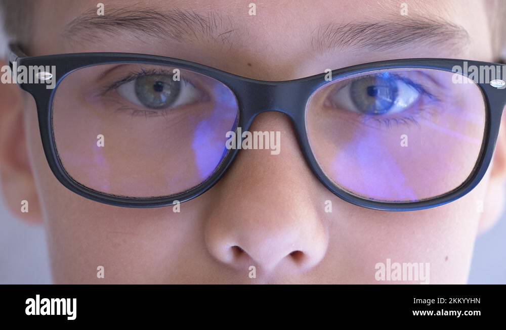 Teenage boy with blue light blocking glasses opening eyes and looking ...