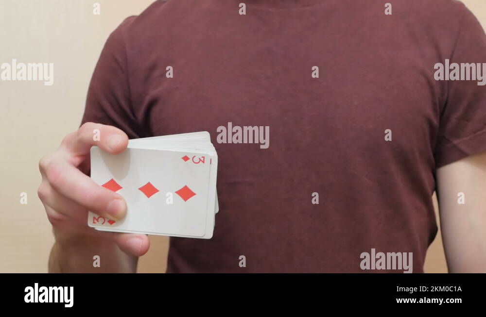 A young magician makes a fan from a deck of cards showing a magic trick ...