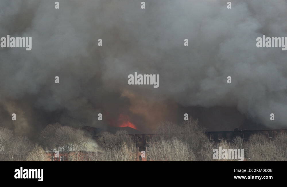 Flames behind the building. Smoke over a burnt-out building. Fire ...