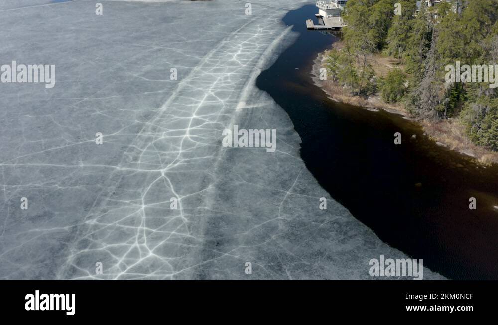 Aerial reveal of ice road remains as warm sunshine melts a frozen lake ...