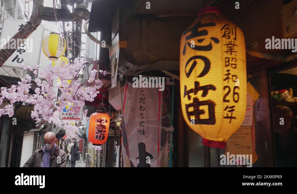 a man walking through a small traditional alley in Tokyo, Japan during ...