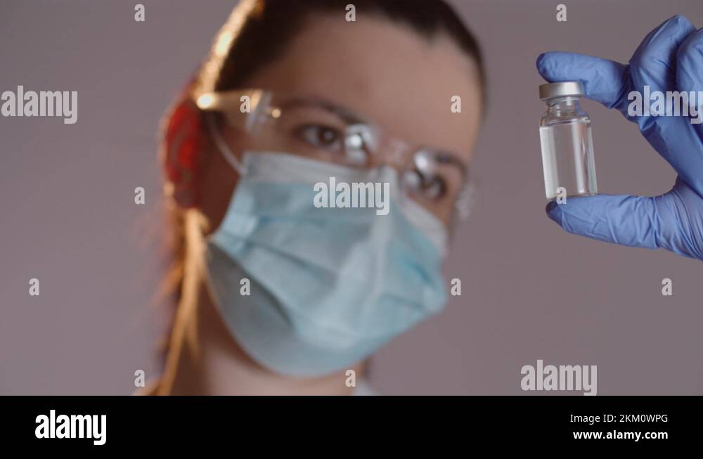 Female doctor or scientist looking at and examining vaccine vial Stock ...