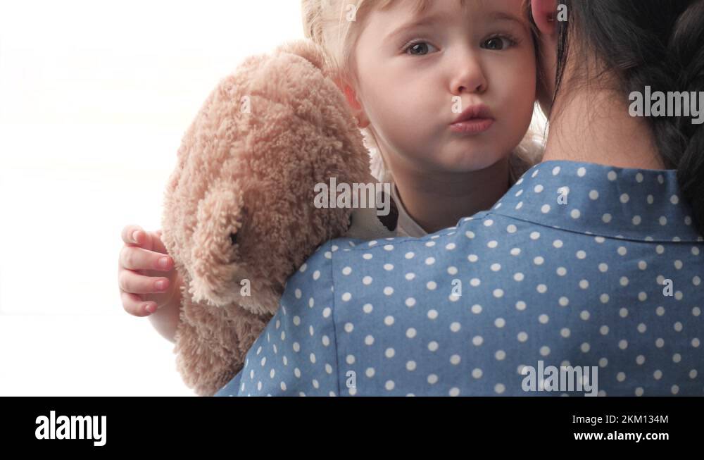 A mother calms a small child holding and shaking a teddy bear with a ...
