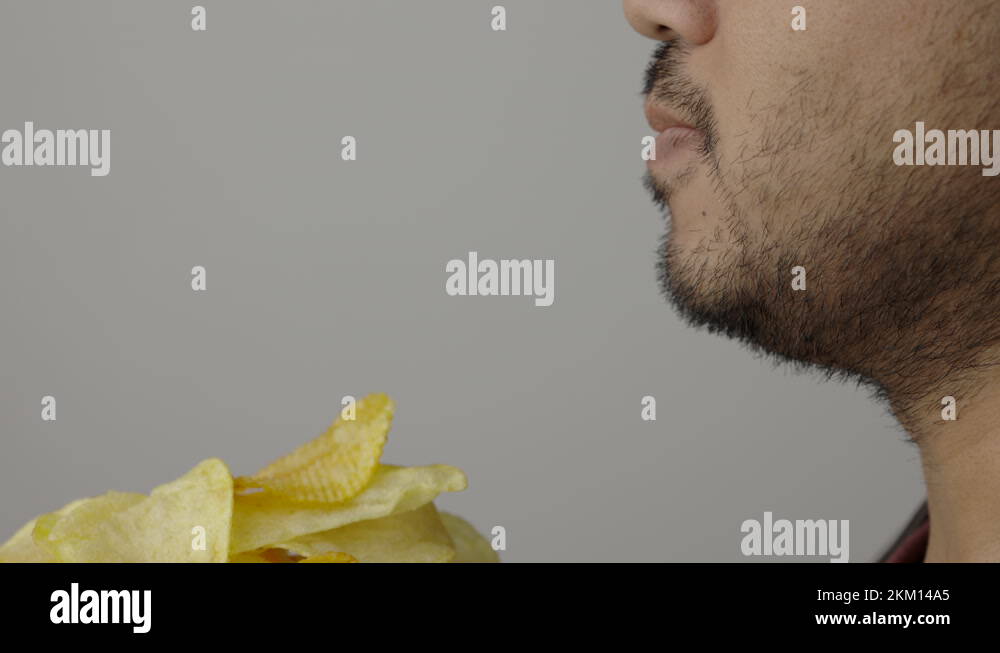Close up mouth Young man eating potato chip in paper bag. Fast food or ...