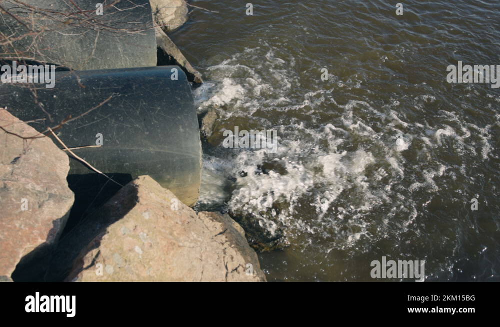 Close view of water flowing out of large sewage pipes into lake Stock ...