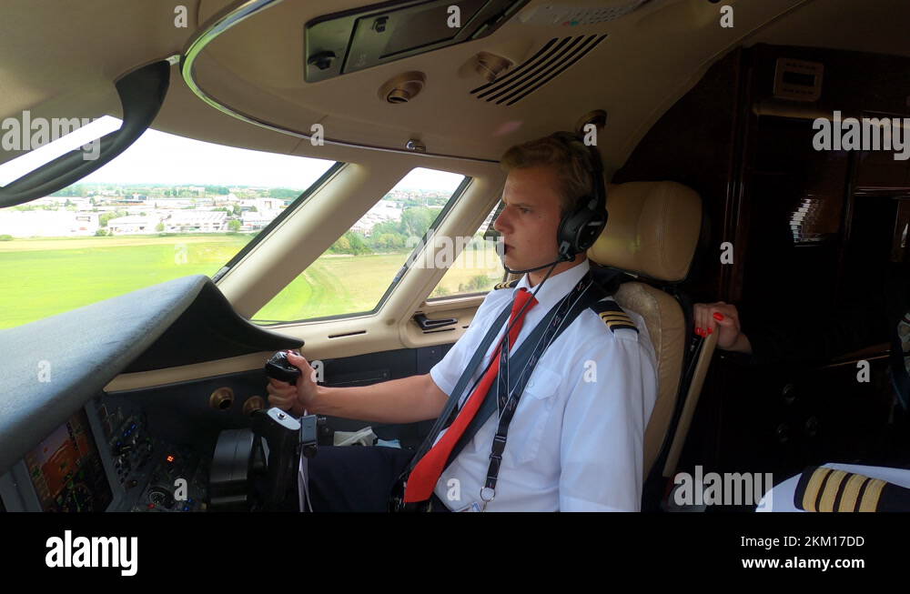 Male pilot, first officer in cockpit landing a jet airplane, hand ...