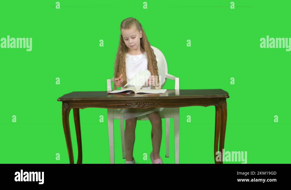 Cute little girl doing homework, writing down on a Green Screen, Chroma ...