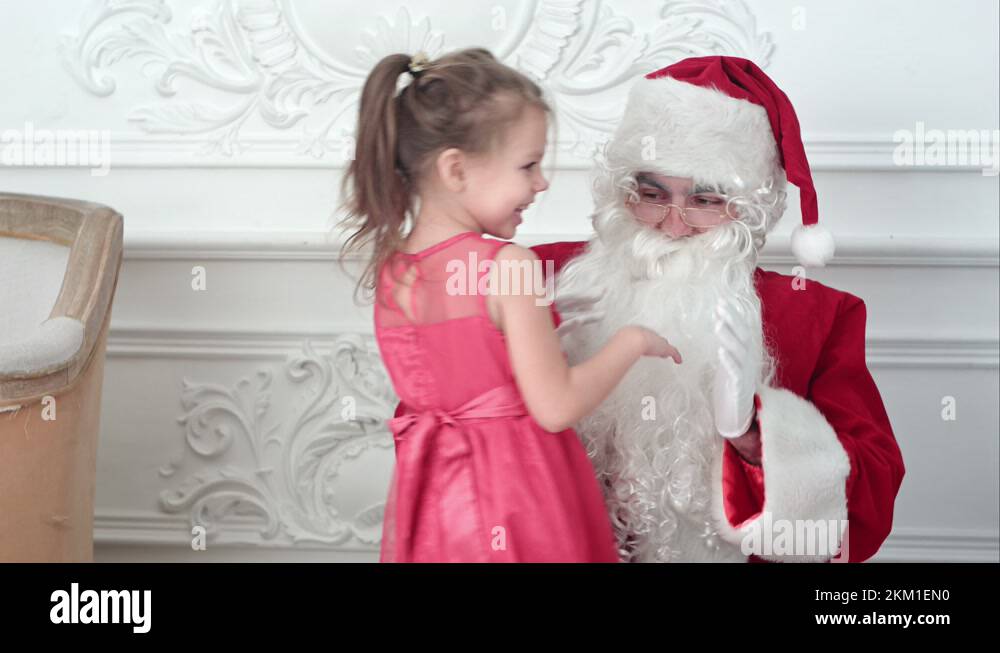 Santa Claus clapping his hands while pretty little girl dancing around ...