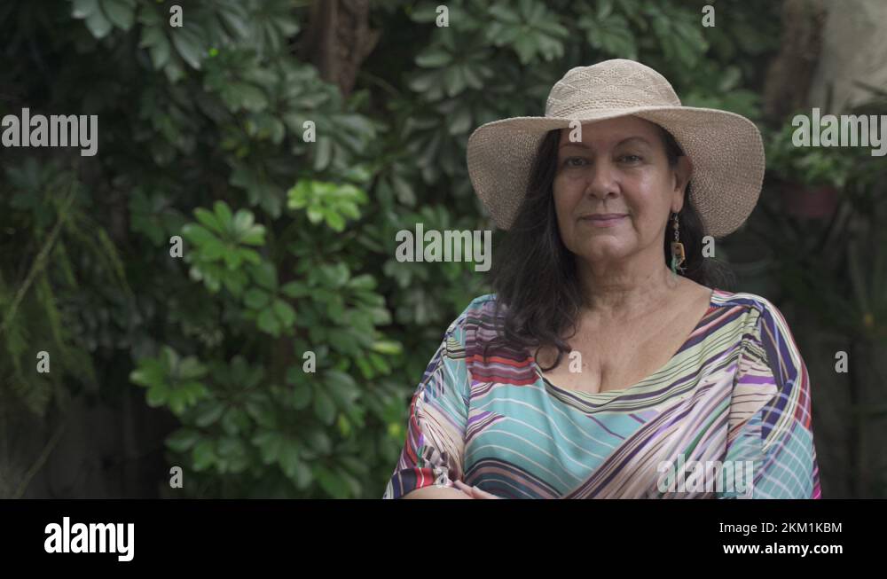 Latin female look at camera and kindly smiles with green background ...