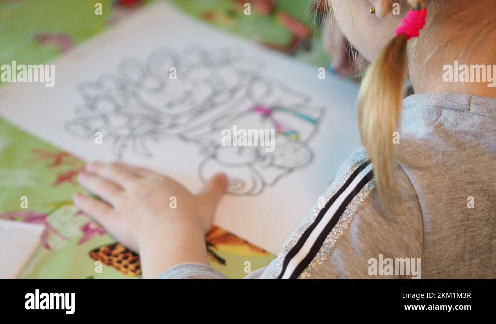 The hands of a little girl who carefully paints the drawing with ...