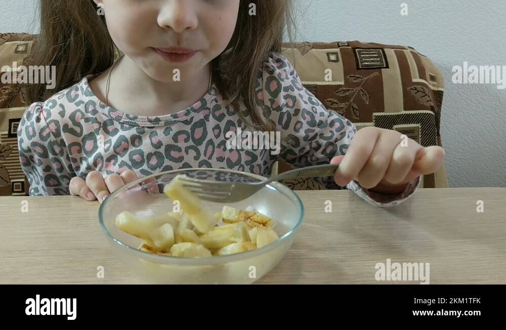 a beautiful little girl with ponytails on her head sits at the dining ...