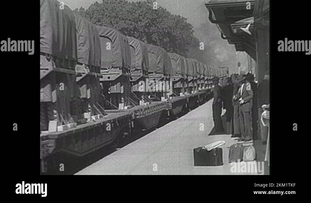 1940s: Trains carry trucks and tanks. People watch from train station ...