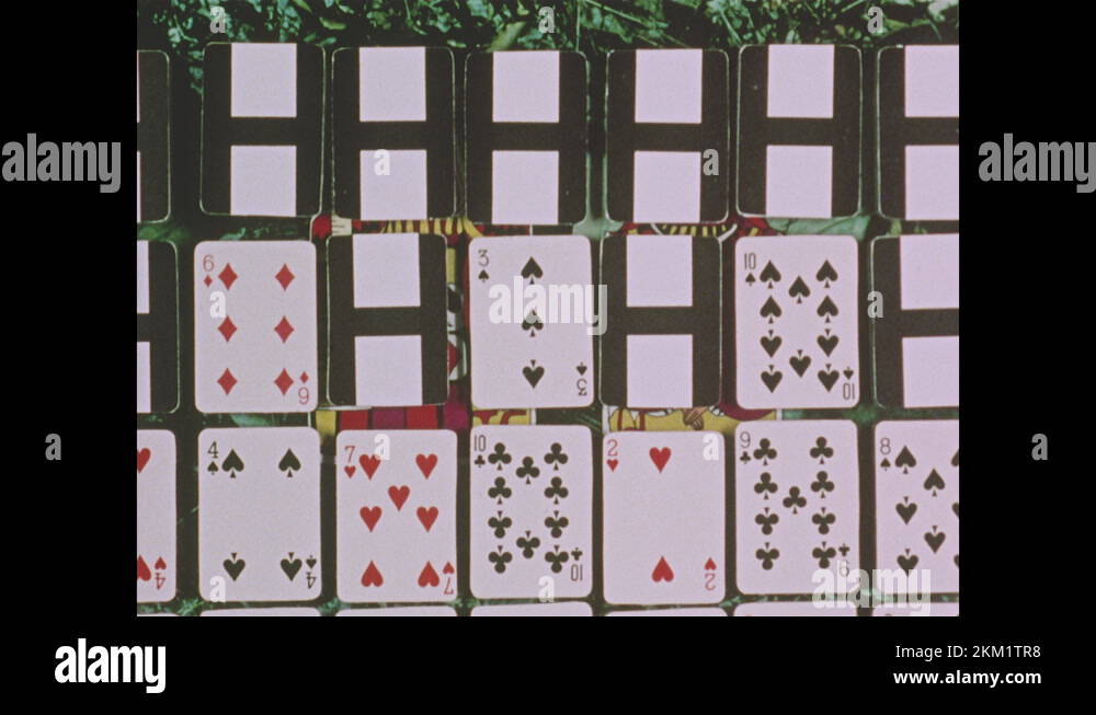 1970s: Playing cards stack up in front of king and queen. King holds ...
