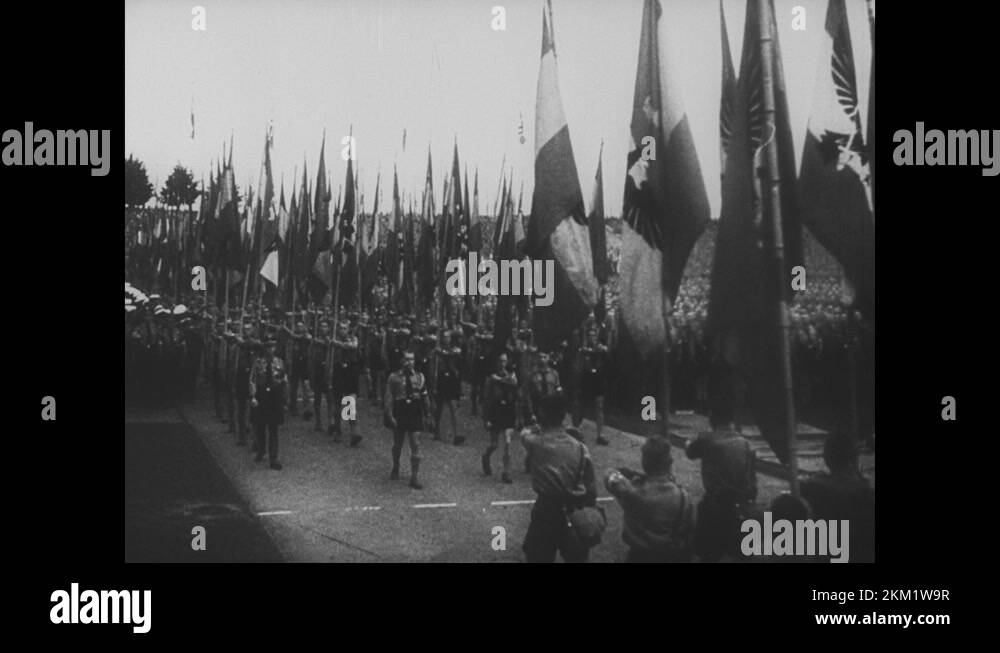1930s: Nazi flags at rally at Nuremberg. Soldiers march holding flags ...