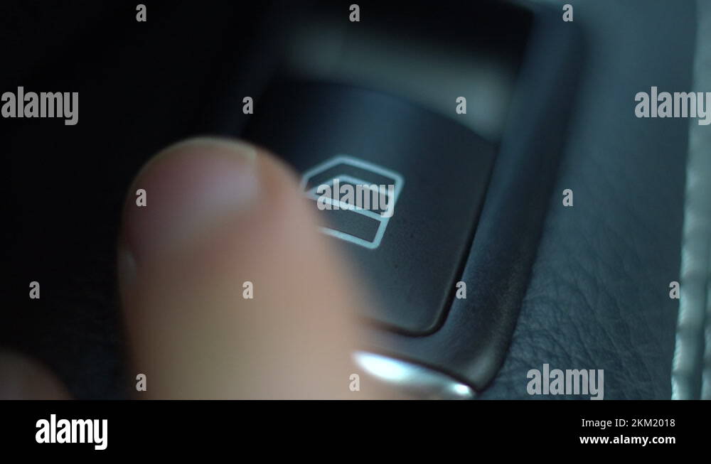Pushing the button to roll up the car window in a luxury automobile ...