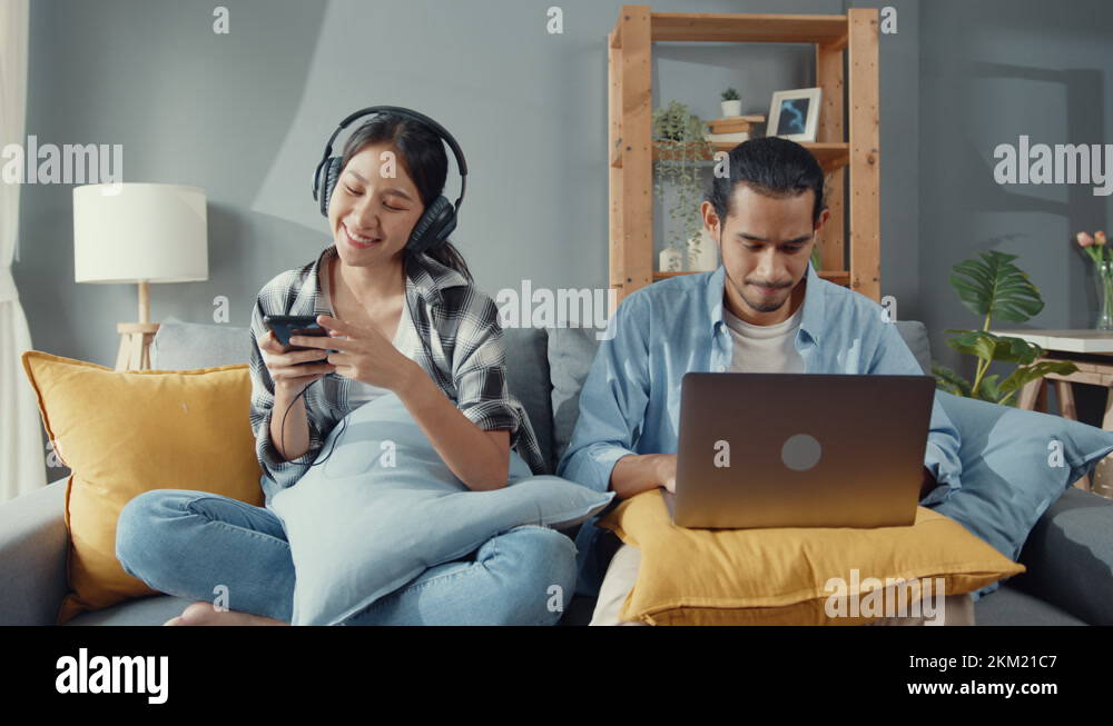 Asia couple man use laptop women wear headphones use smartphone listen ...