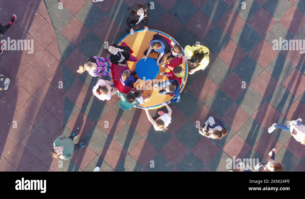 Kids spinning on merry-go-round at a playground in a park, busy with ...