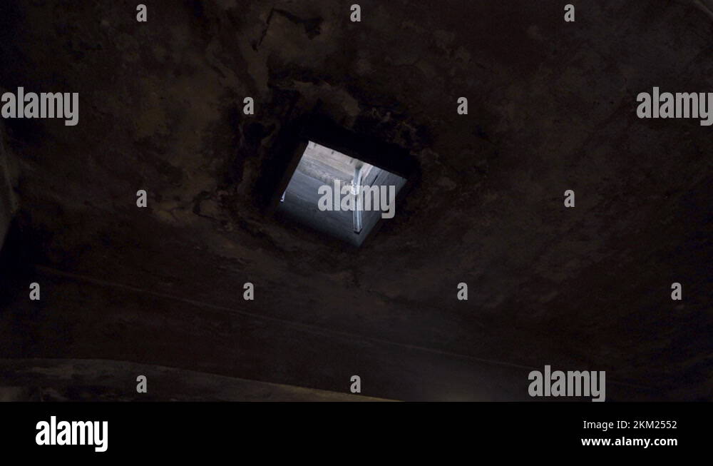 Pan down from hole in gas chamber ceiling to tourists walking through ...