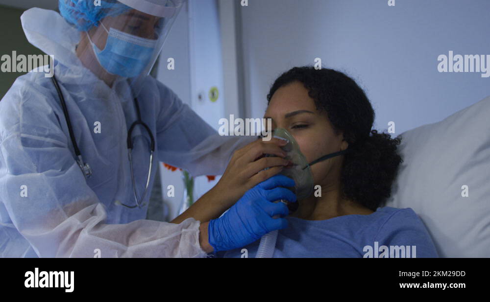 Caucasian female doctor putting on oxygen mask ventilator on african american Stock Video ...
