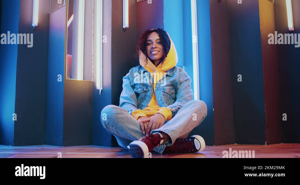 Stylish female sitting on floor moves rhythmically to music beat in ...