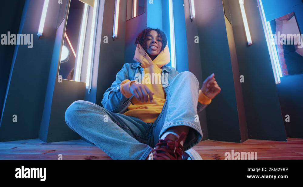 Stylish urban female sitting on floor dancing moves to music beat in ...