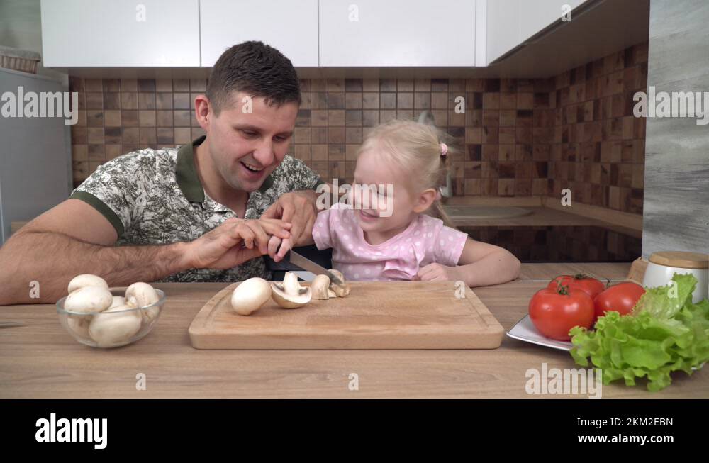 Father and child are cooking in the kitchen. Dad teaches his daughter ...