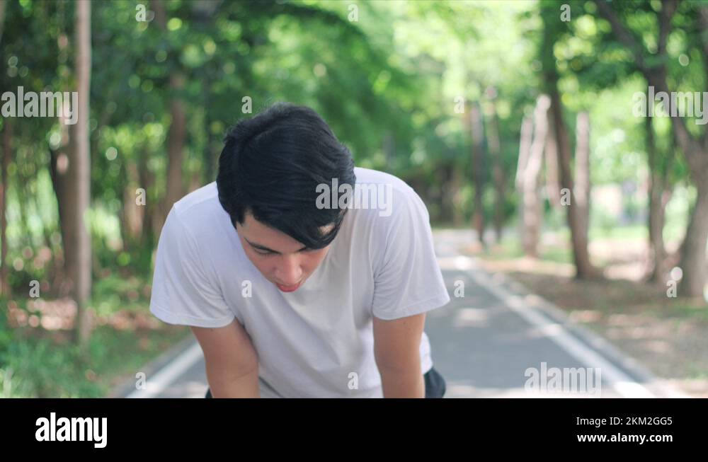 Asian man finishing running and bending over to catch breath Stock ...