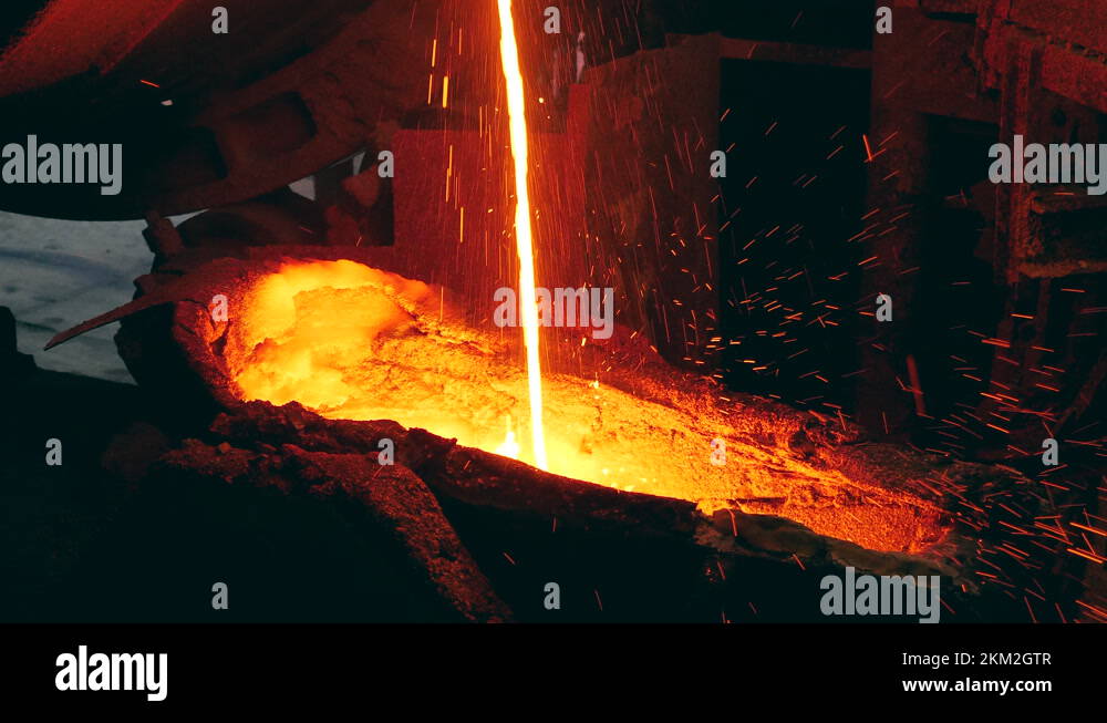 Melted metal is flowing from the industrial tank. Metallurgy concept ...