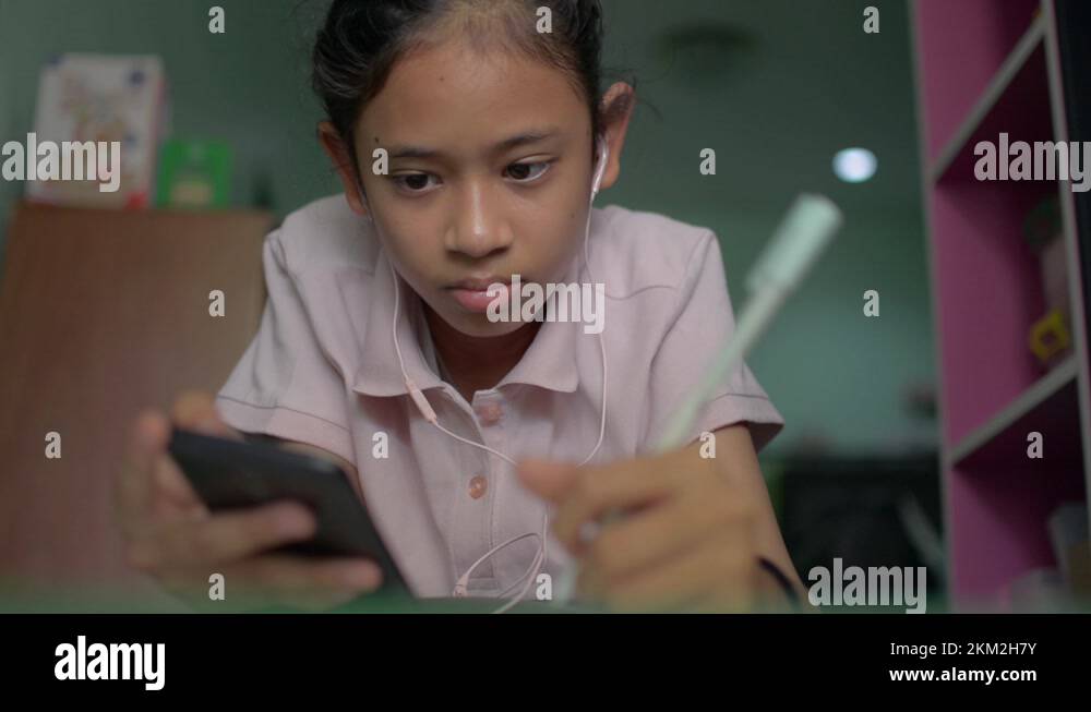 Pretty girl wearing earphone studying with lesson online from mobile phone Stock Video Footage ...