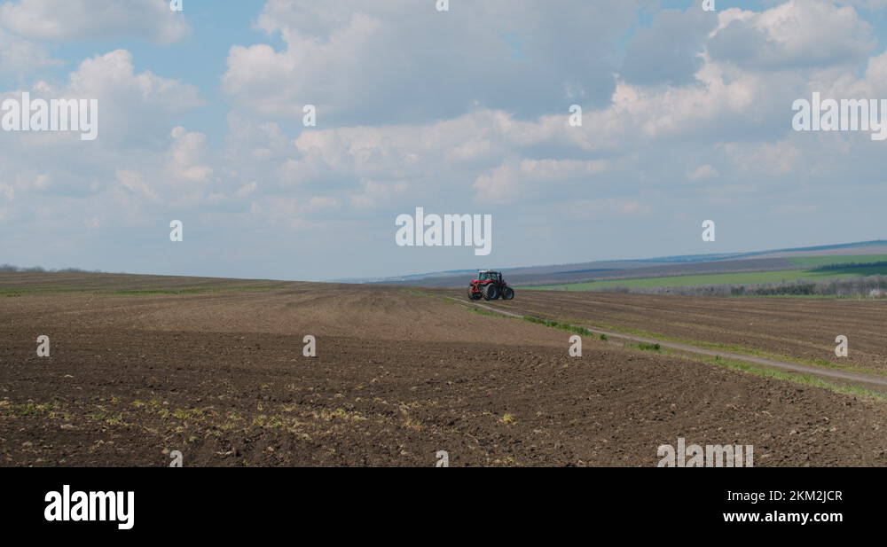 A modern and red tractor on the agricultural field. A farmer on the ...