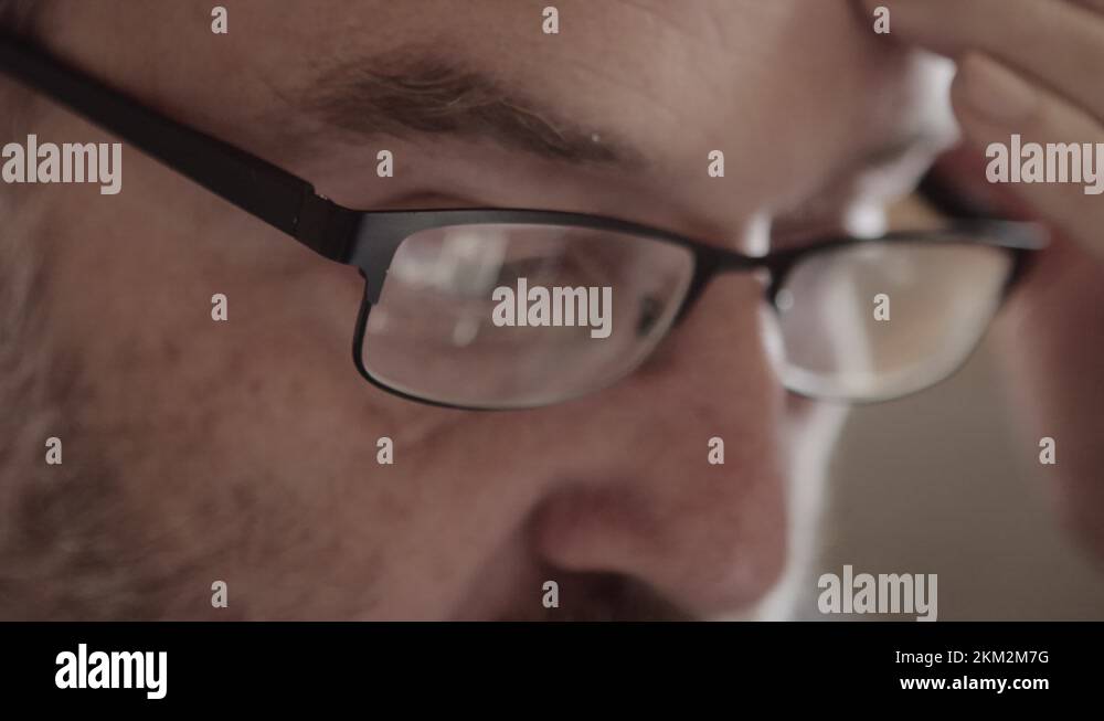 Man scrolls on screen, the reflection is seen in his glasses, close up ...
