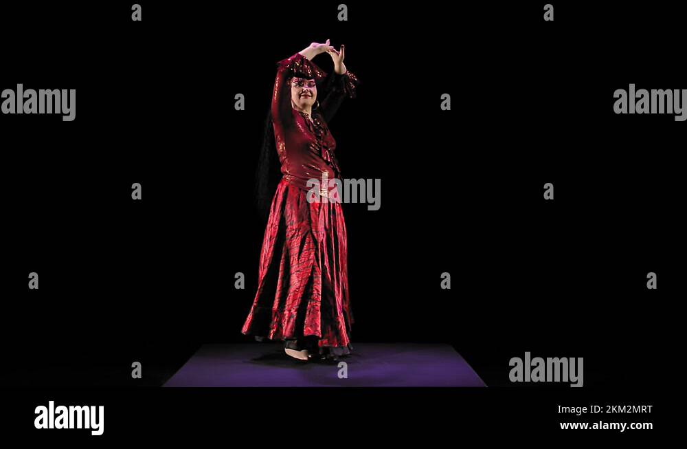A barefoot gypsy woman with long hair in a red suit dances beautifully ...