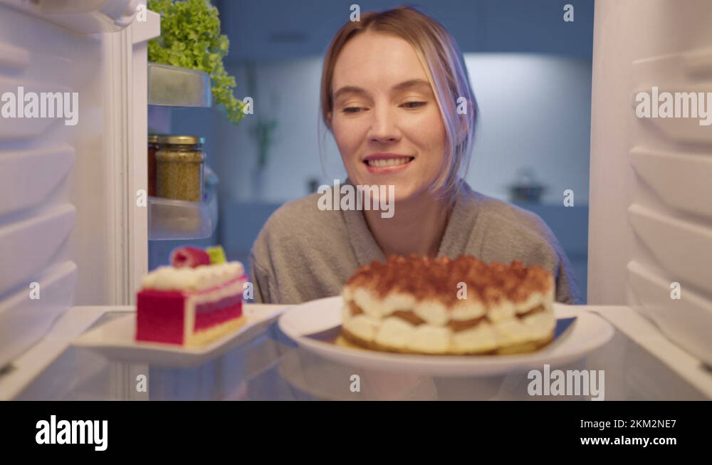 Sweet tooth woman at midnight opening refrigerator and cant stop eating ...