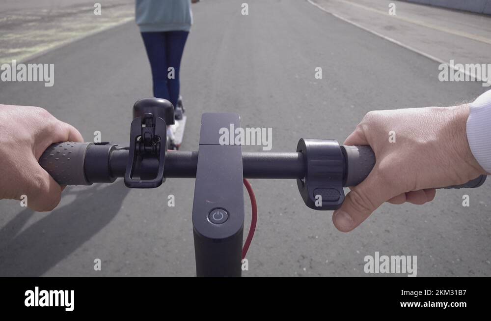 First-person view. A man follows a woman on his electric scooter Stock ...