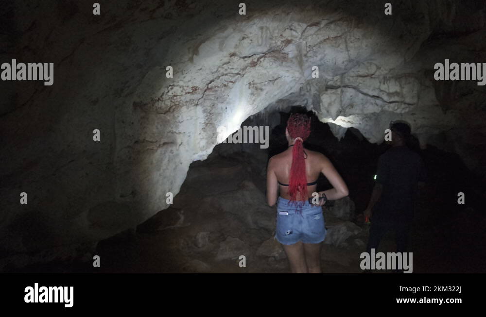 Woman Explores Stalactites Inside a Deep Dark Cave, Illuminating with ...