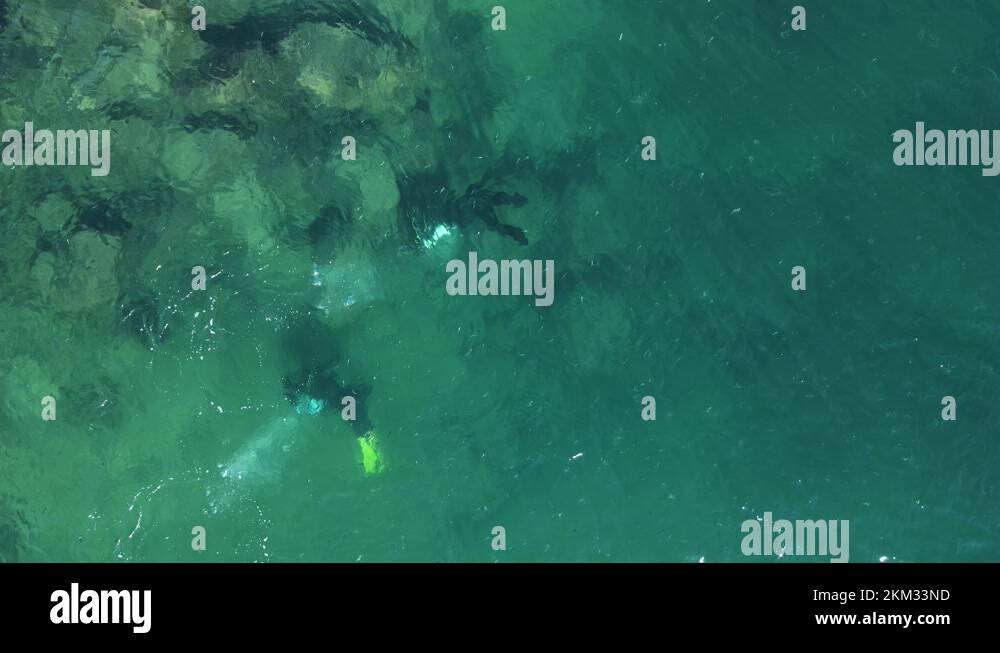Unique view of scuba divers below the water exploring a man-made Stock ...