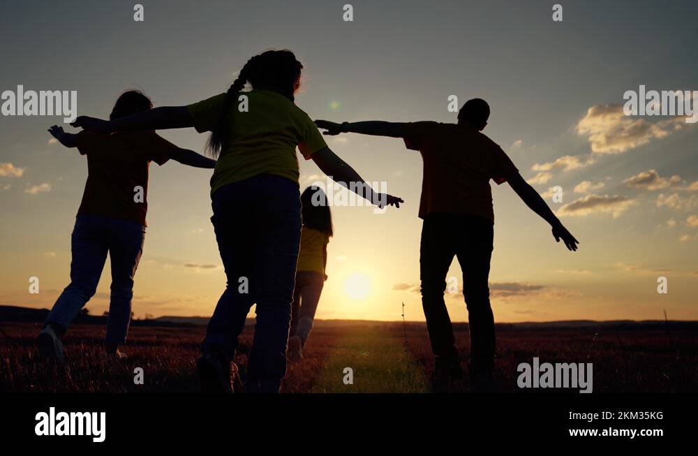 Silhouette of happy family. Family run in field in park. Silhouette of ...