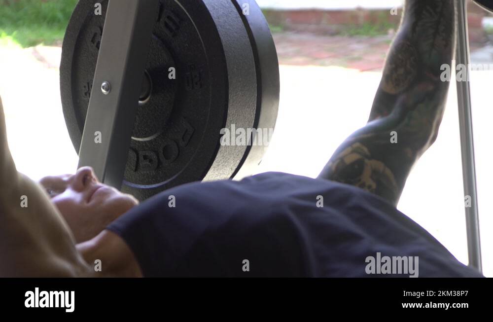 Muscly man in home gym exercising smith machine bench press close up ...