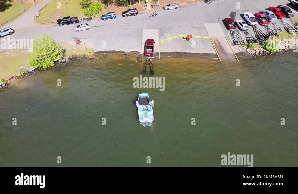 Wakeboard boat being loaded on a trailer at the boat ramp. Crowded lake ...
